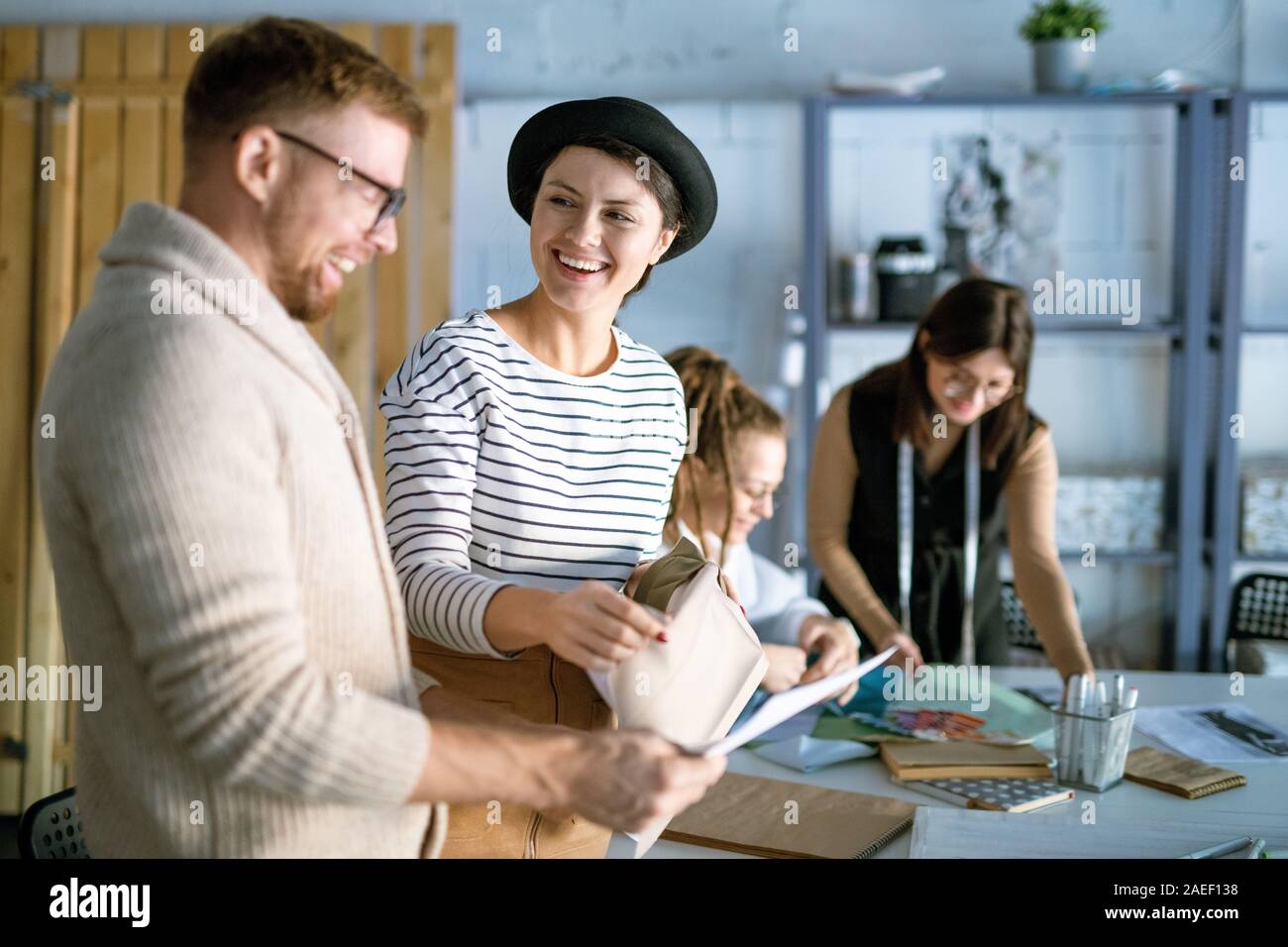 Cheerful female and her colleague choosing textile for new fashion ...