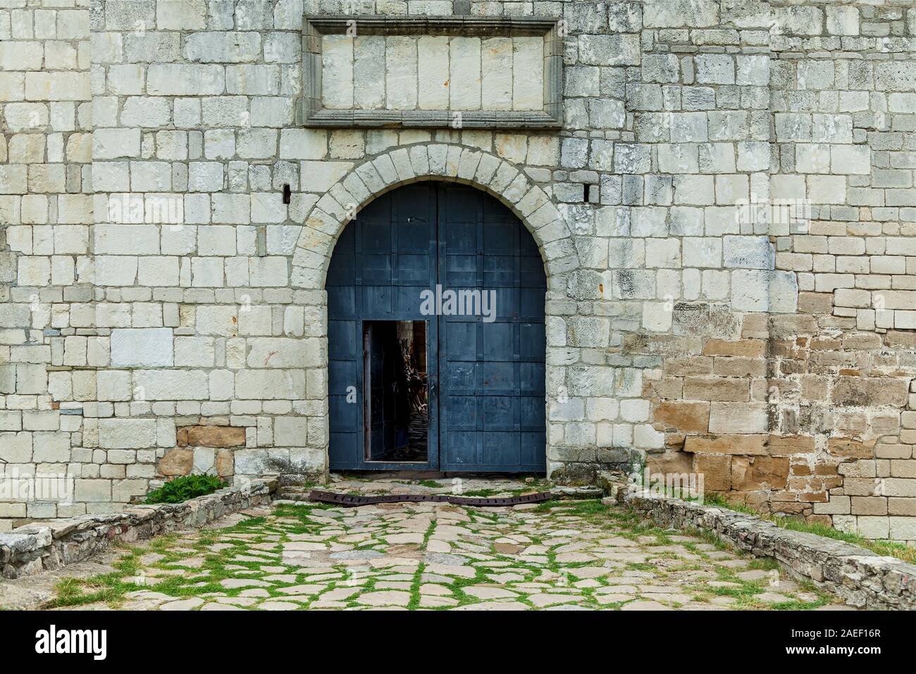 The stone wall with an ancient iron gate on the dark color. The major ...
