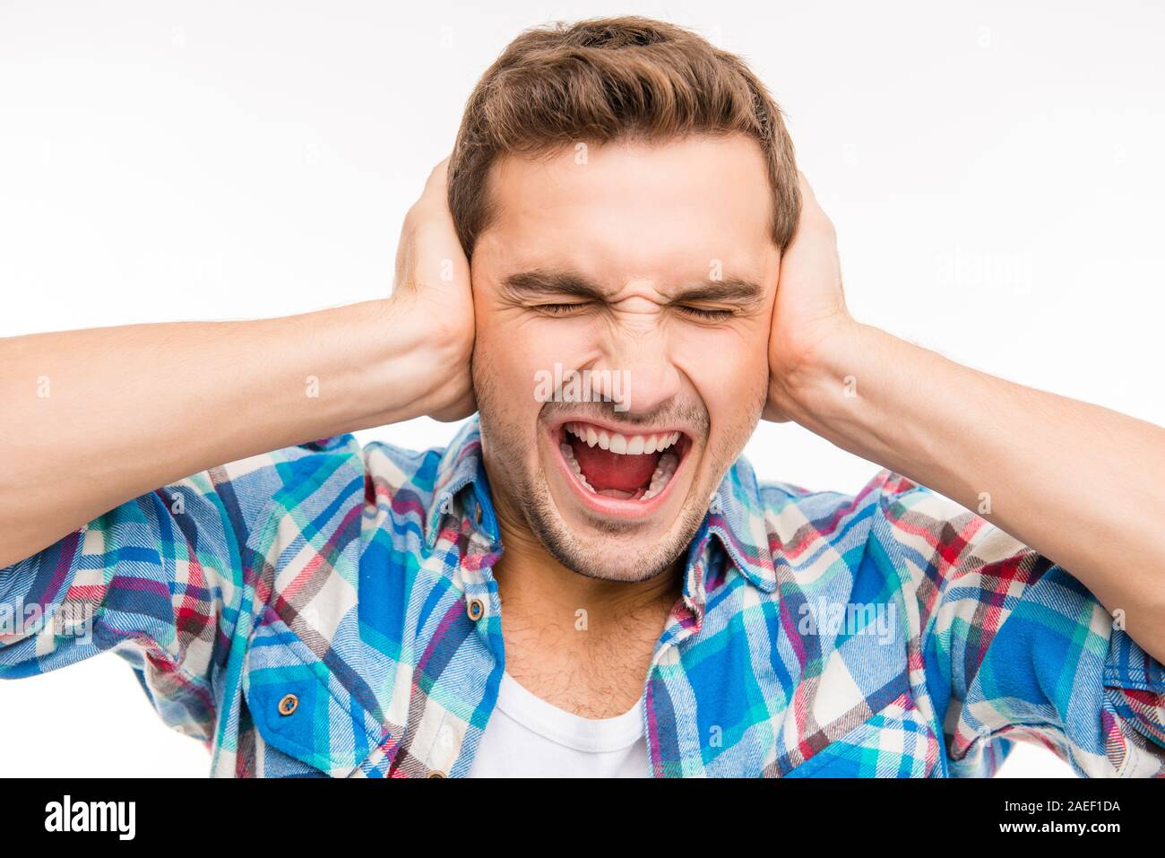 Young man covering his ears and shouting Stock Photo - Alamy
