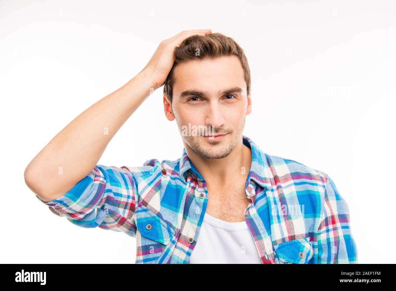Handsome cheerful young man holding hand on his hair Stock Photo - Alamy
