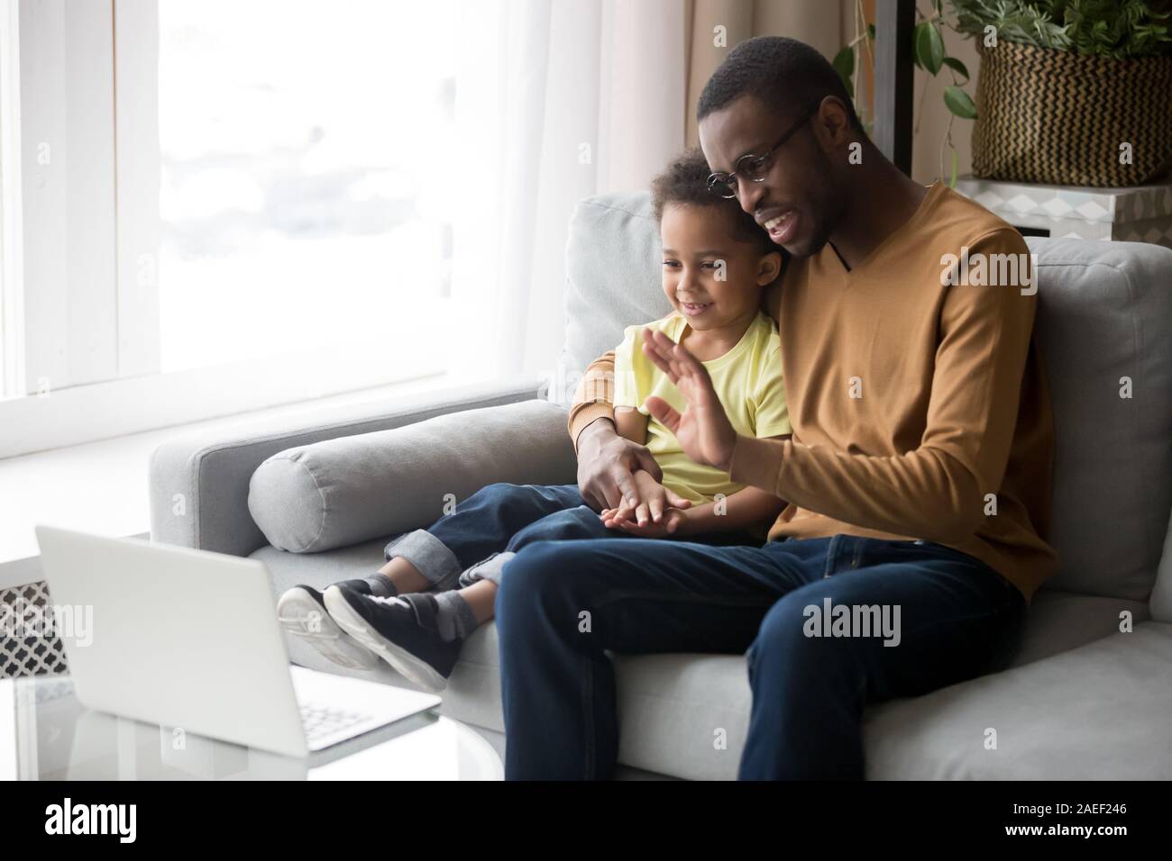 Smiling black dad and son wave talking on webcam Stock Photo - Alamy