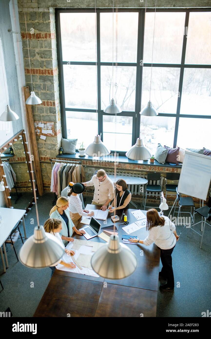 Group of contemporary creative designers gathered by table in studio ...