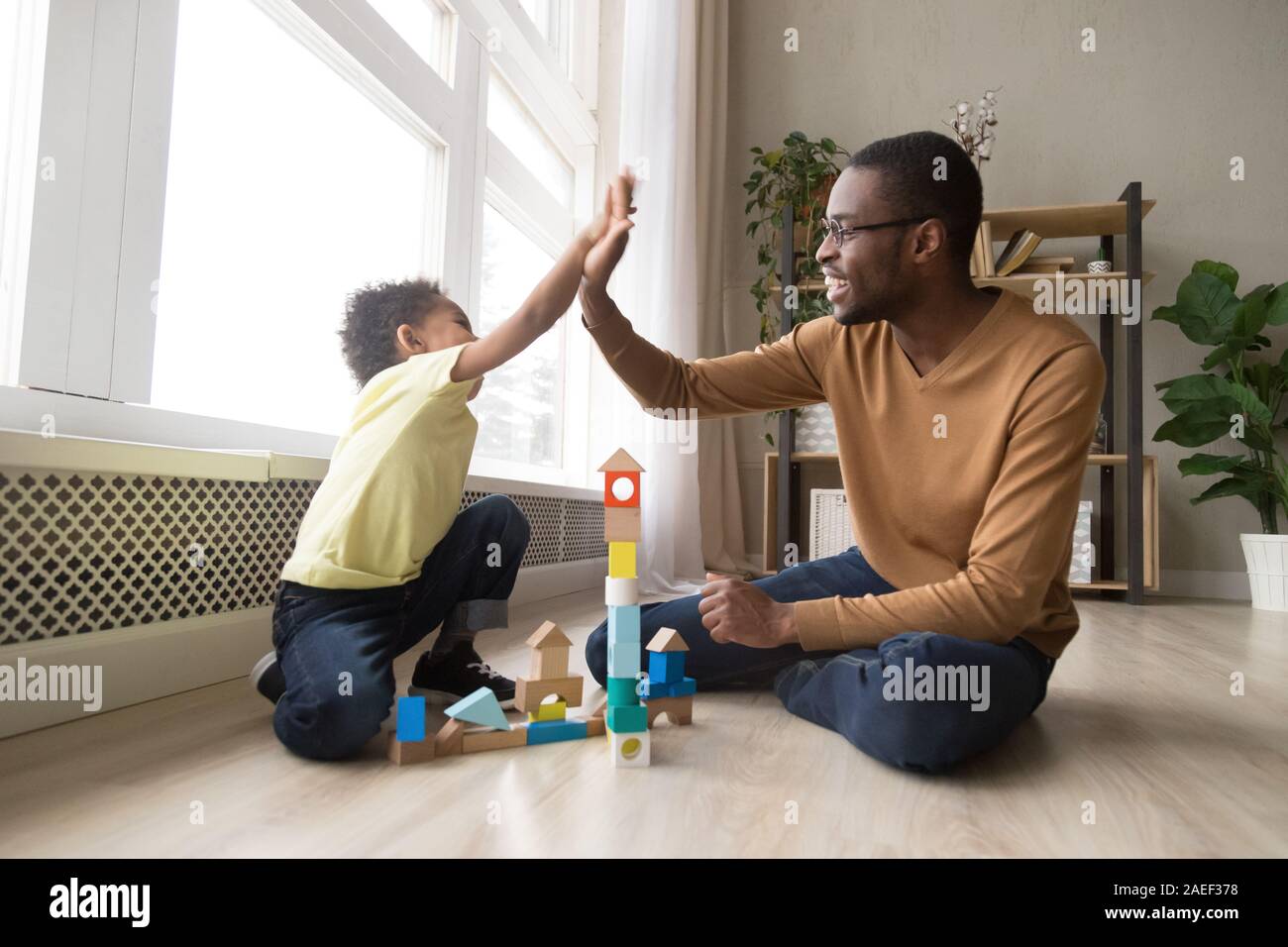 Excited black dad and son give high five playing together Stock Photo ...