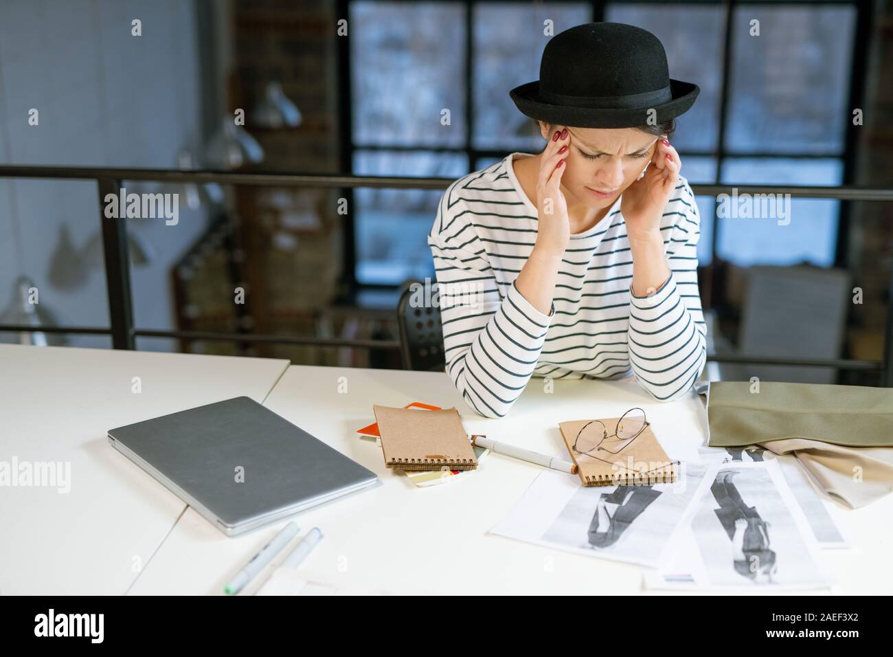 Tired designer in casualwear trying to concentrate while thinking of ...