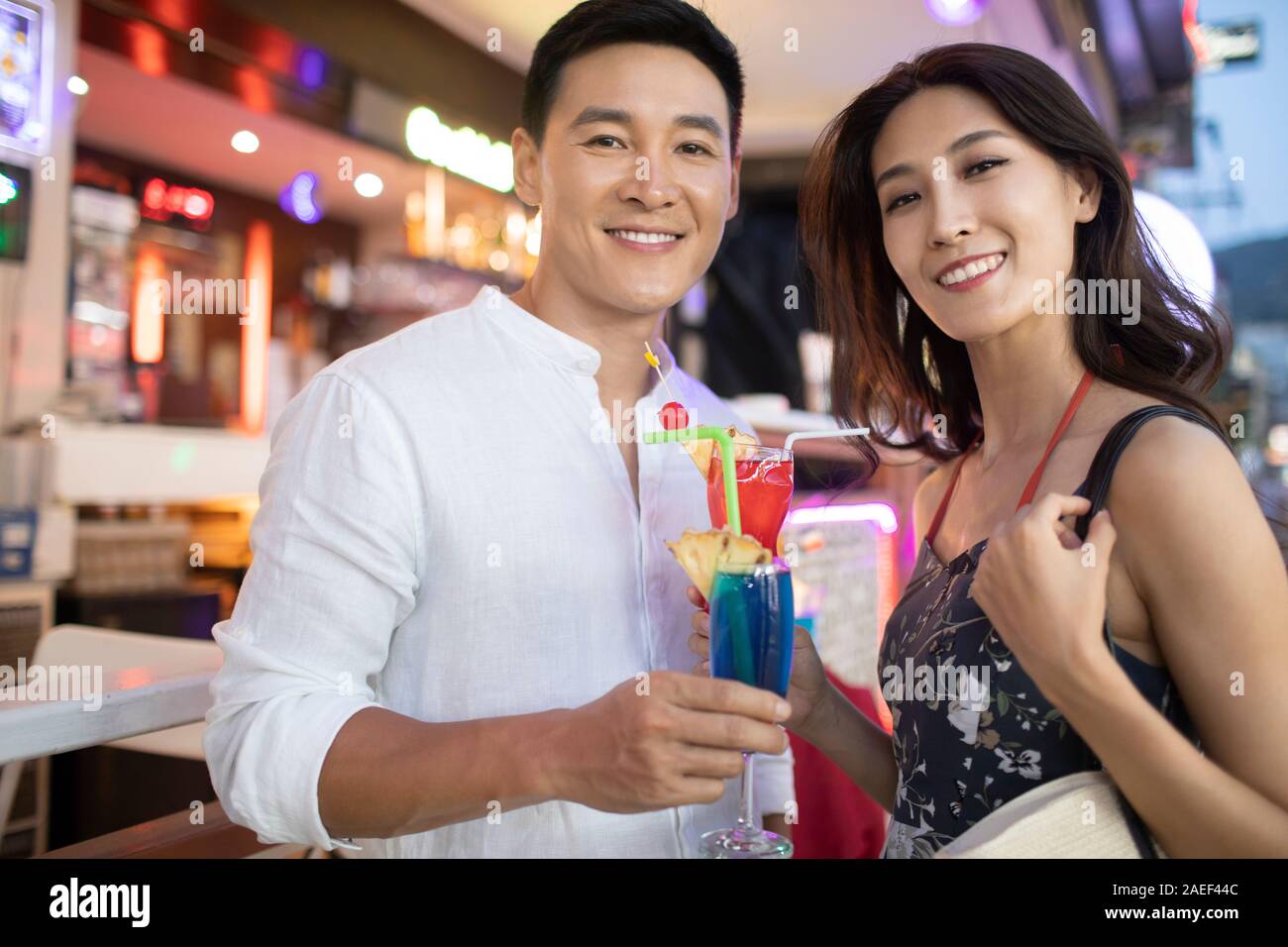 Happy young couple drinking cocktail at night market Stock Photo - Alamy
