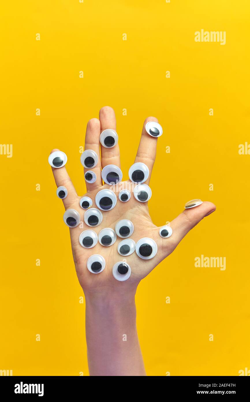 Woman's hand with plastic eyes and gesture from fingers on an yellow ...