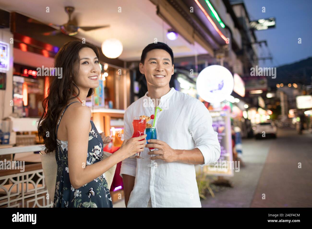 Happy young couple drinking cocktail at night market Stock Photo - Alamy