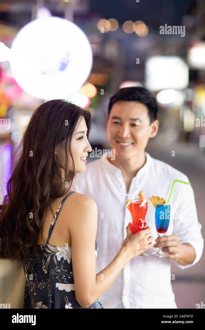 Happy young couple drinking cocktail at night market Stock Photo - Alamy