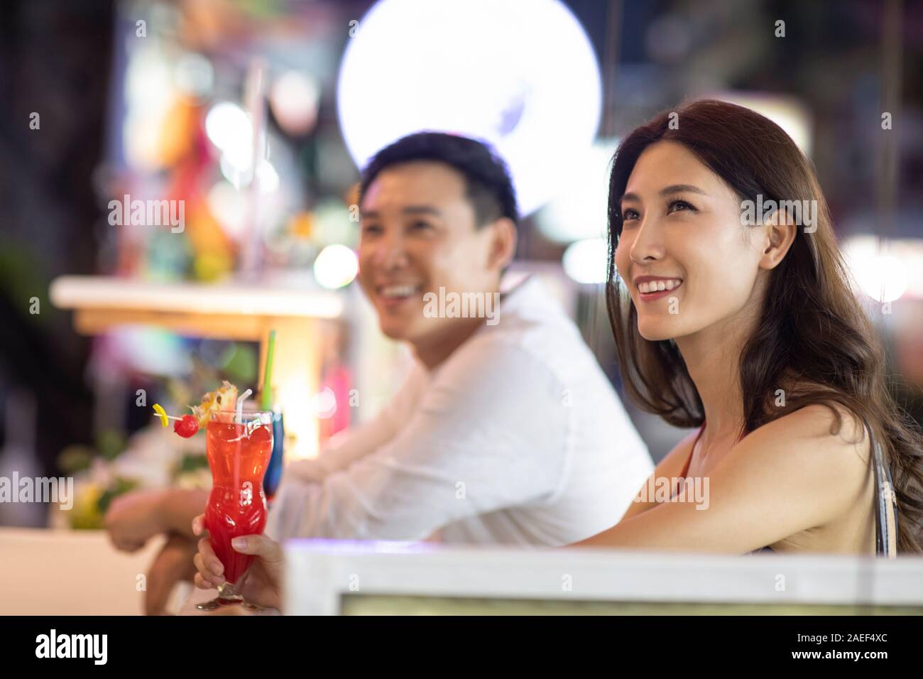Happy young couple drinking cocktail at night market Stock Photo - Alamy