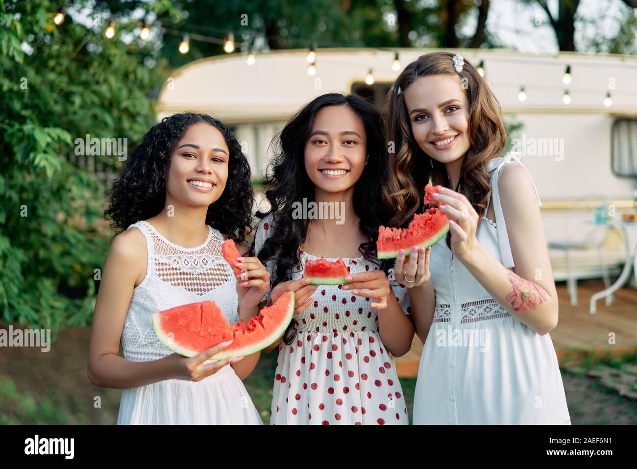 Different ethnics women enjoying a watermelon. Female friends eating a ...