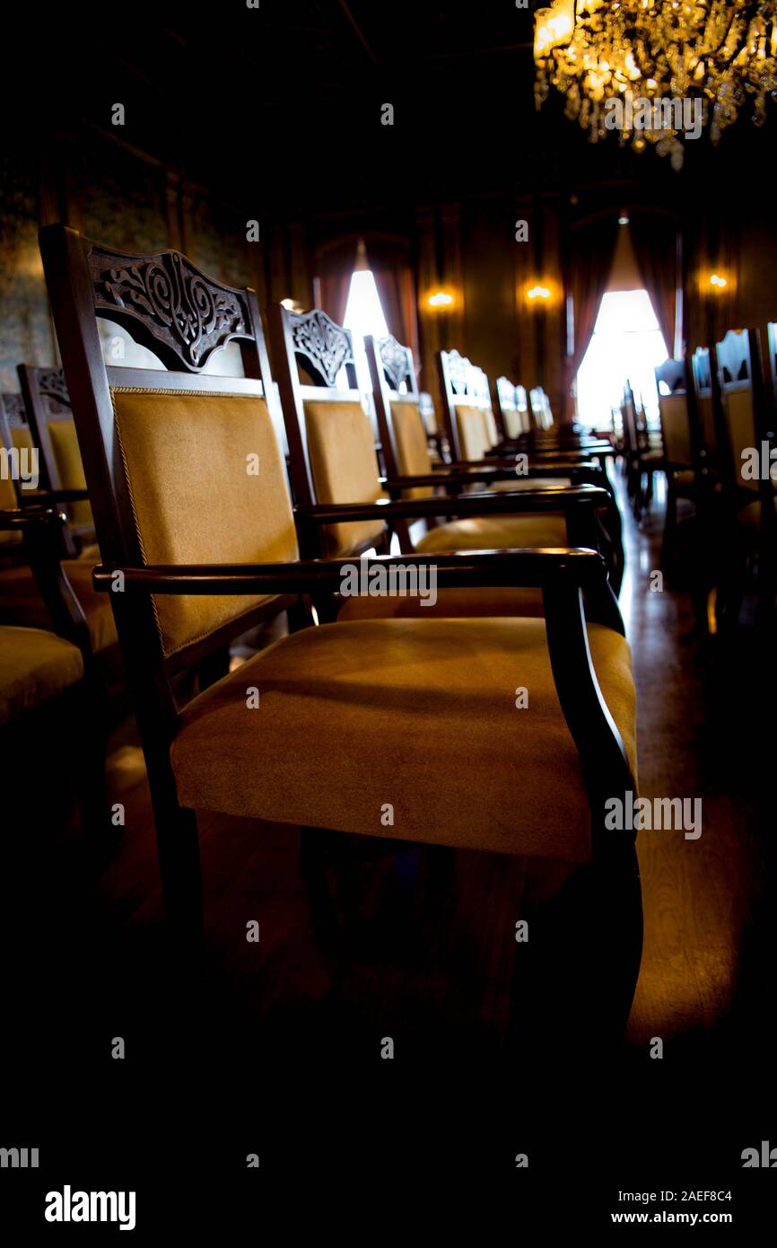 A series of classical wooden chairs in dark classical interior. Top ...