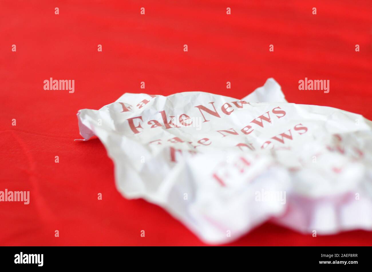 Fake news written in white paper lying against color background with ...