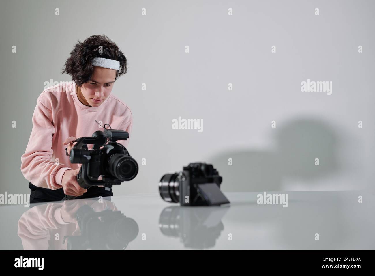 Young serious video blogger standing in front of new photo equipment on ...