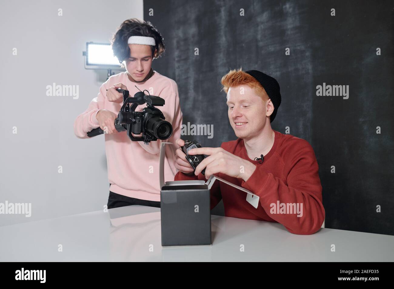 Young cameraman shooting happy male vlogger holding new photocamera ...
