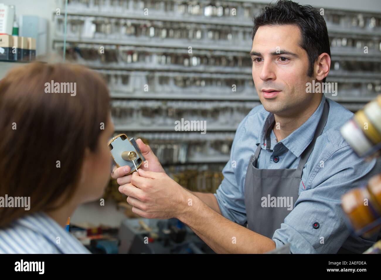 cobbler holding lock and key talking to female client Stock Photo - Alamy