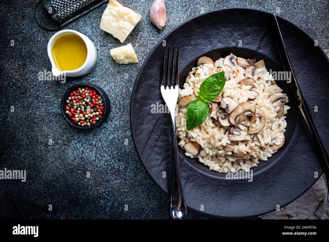 Risotto with mushrooms in a black plate over dark background, top view ...