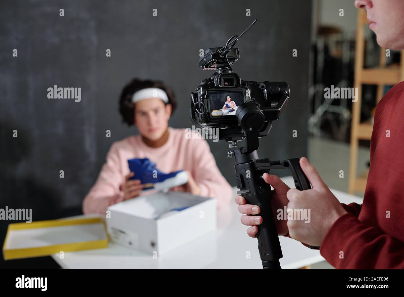 Young man holding video camera while standing in front of vlogger by ...