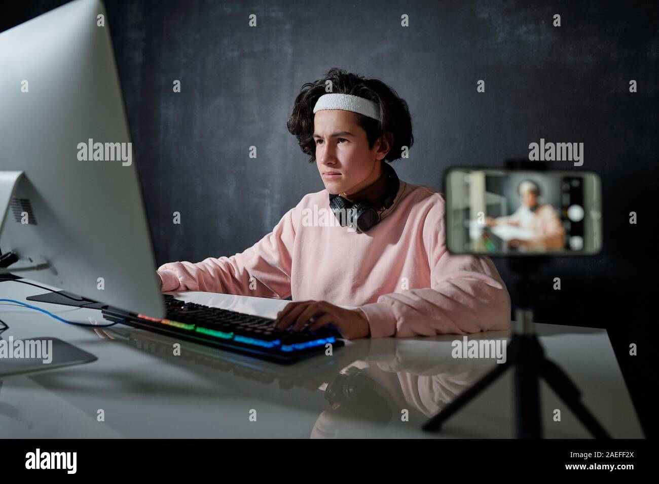Young serious man in casualwear looking at computer screen while typing ...