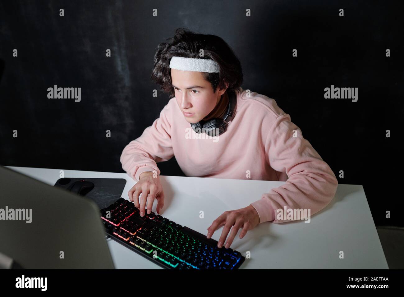 Serious teenager with headphones around neck pressing keys of keypad ...