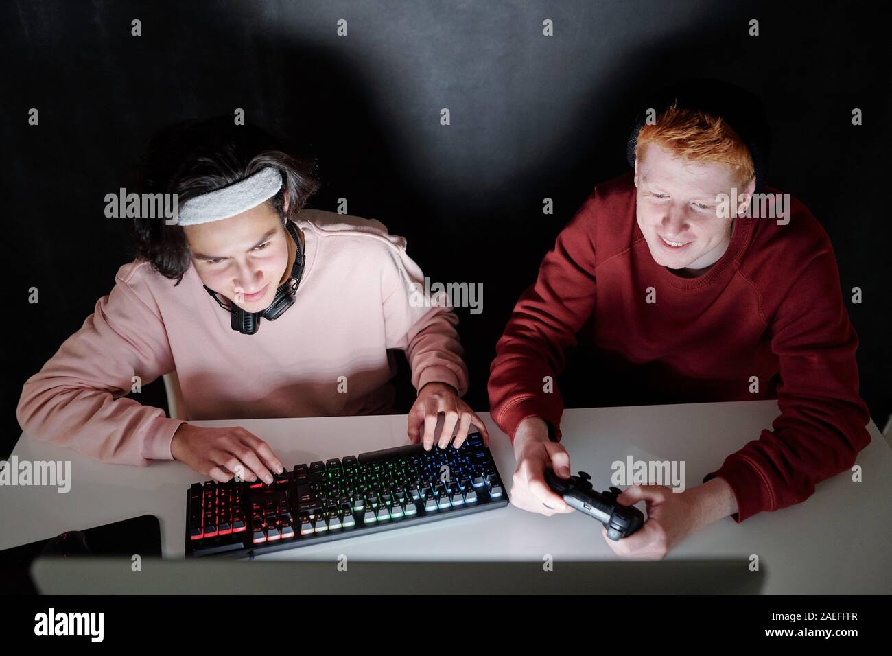 Two friendly teenagers in casualwear sitting by desk in front of ...
