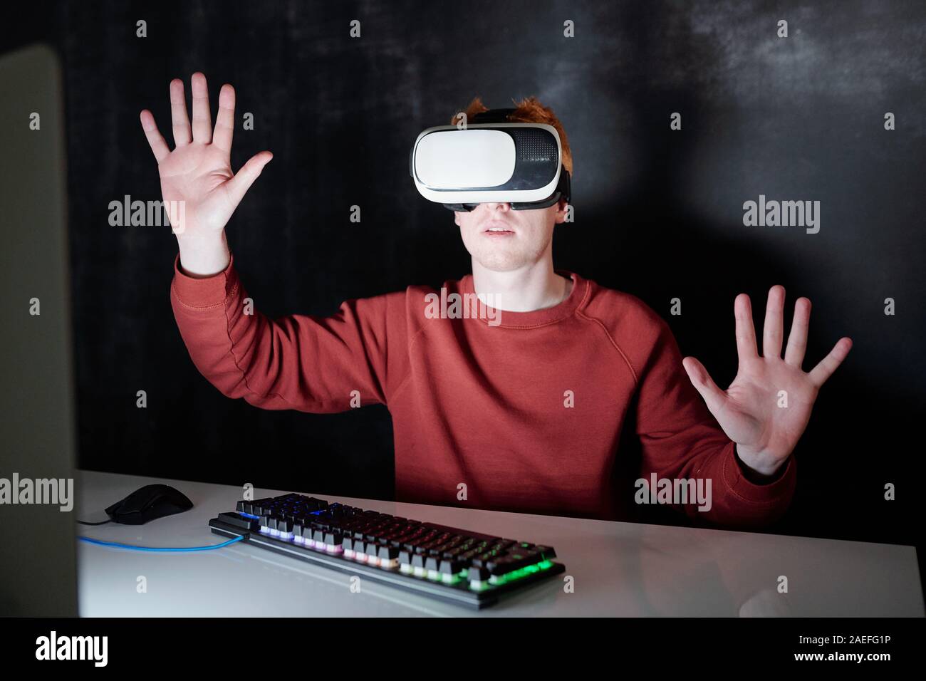 Young man in vr headsets sitting by desk in front of virtual computer ...