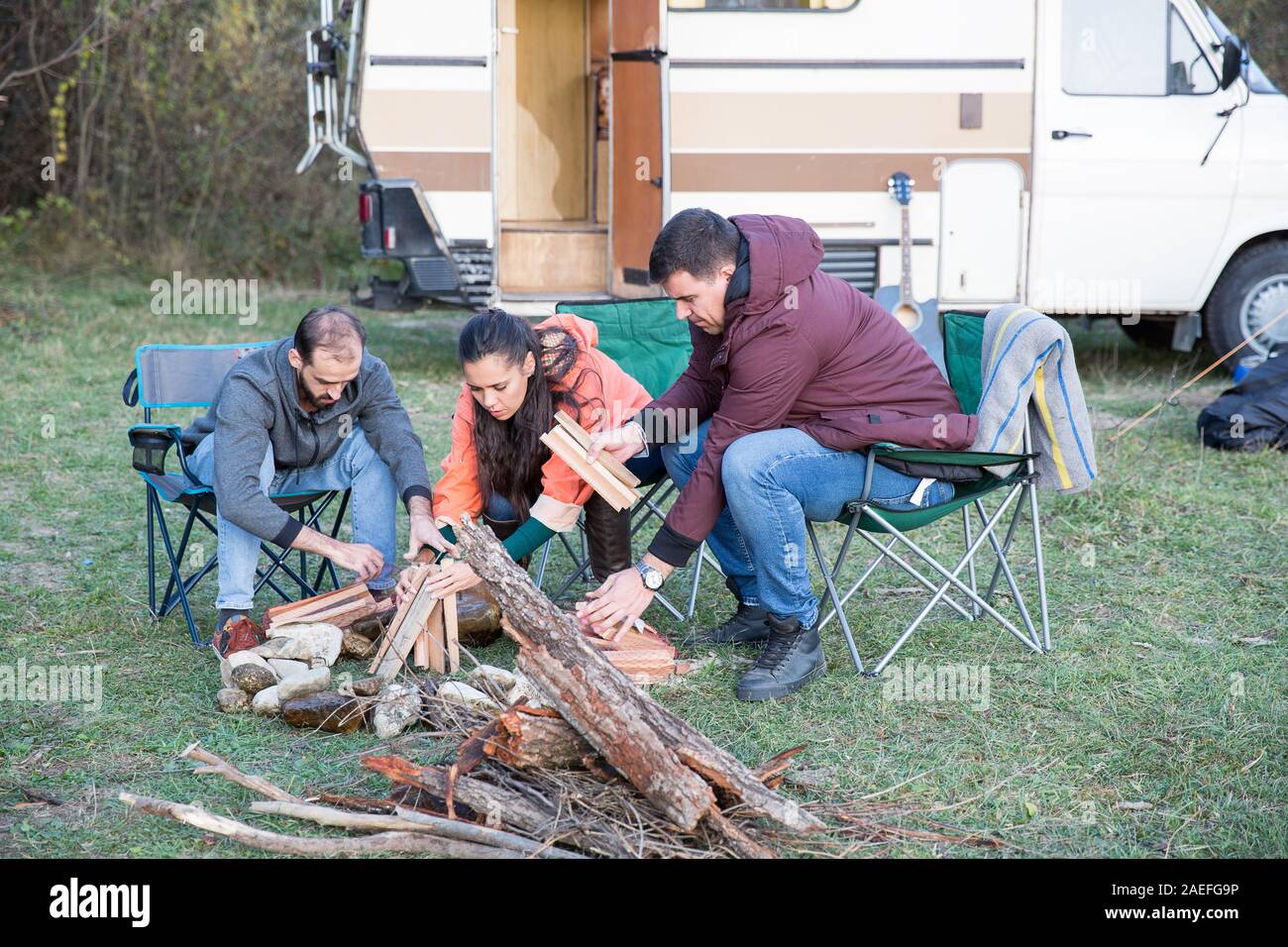 Group of close friends setting up the camp fire in the woods with retro ...
