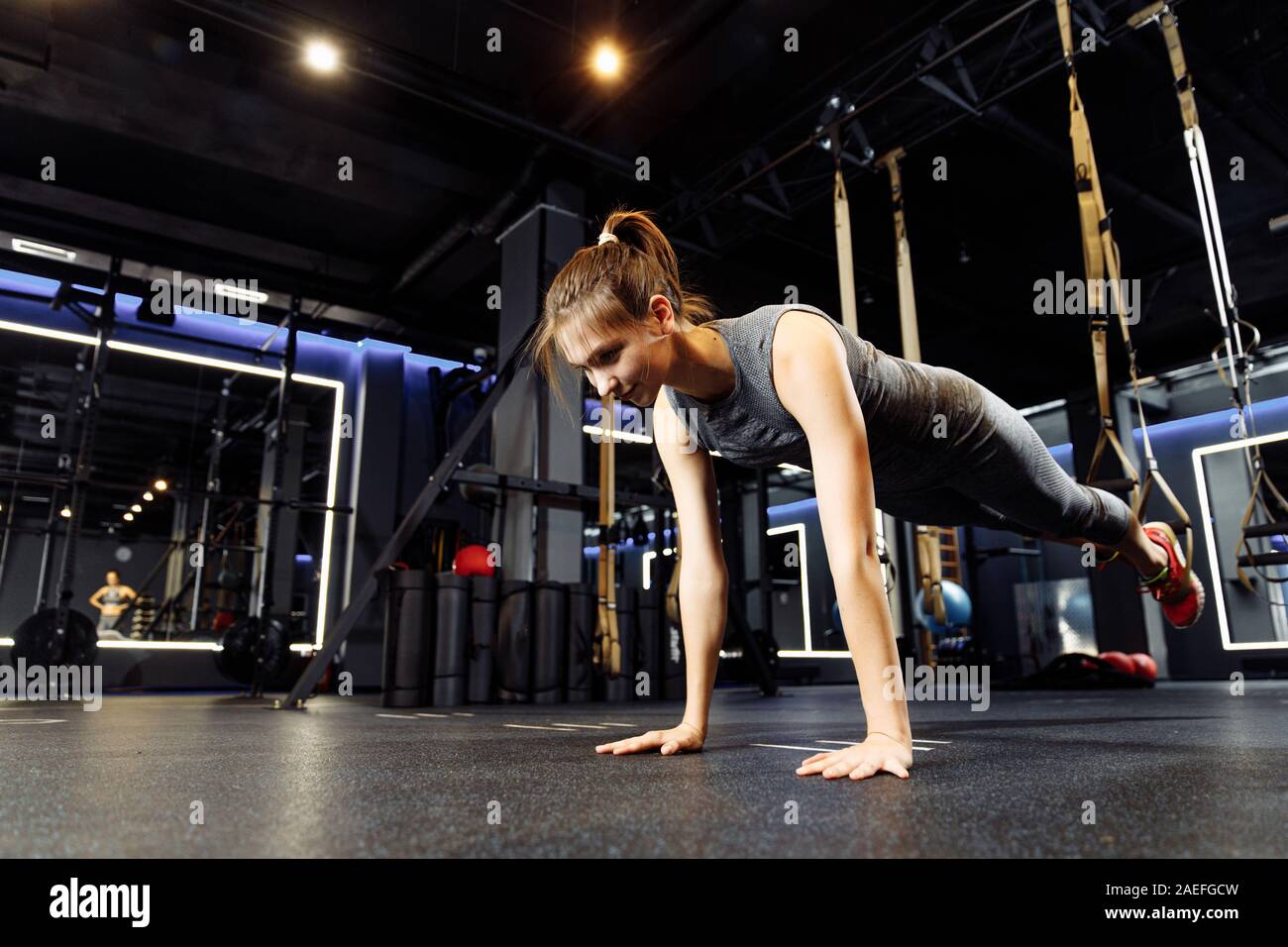 Young athletic girl stretching with elastic bands in gym on dark ...