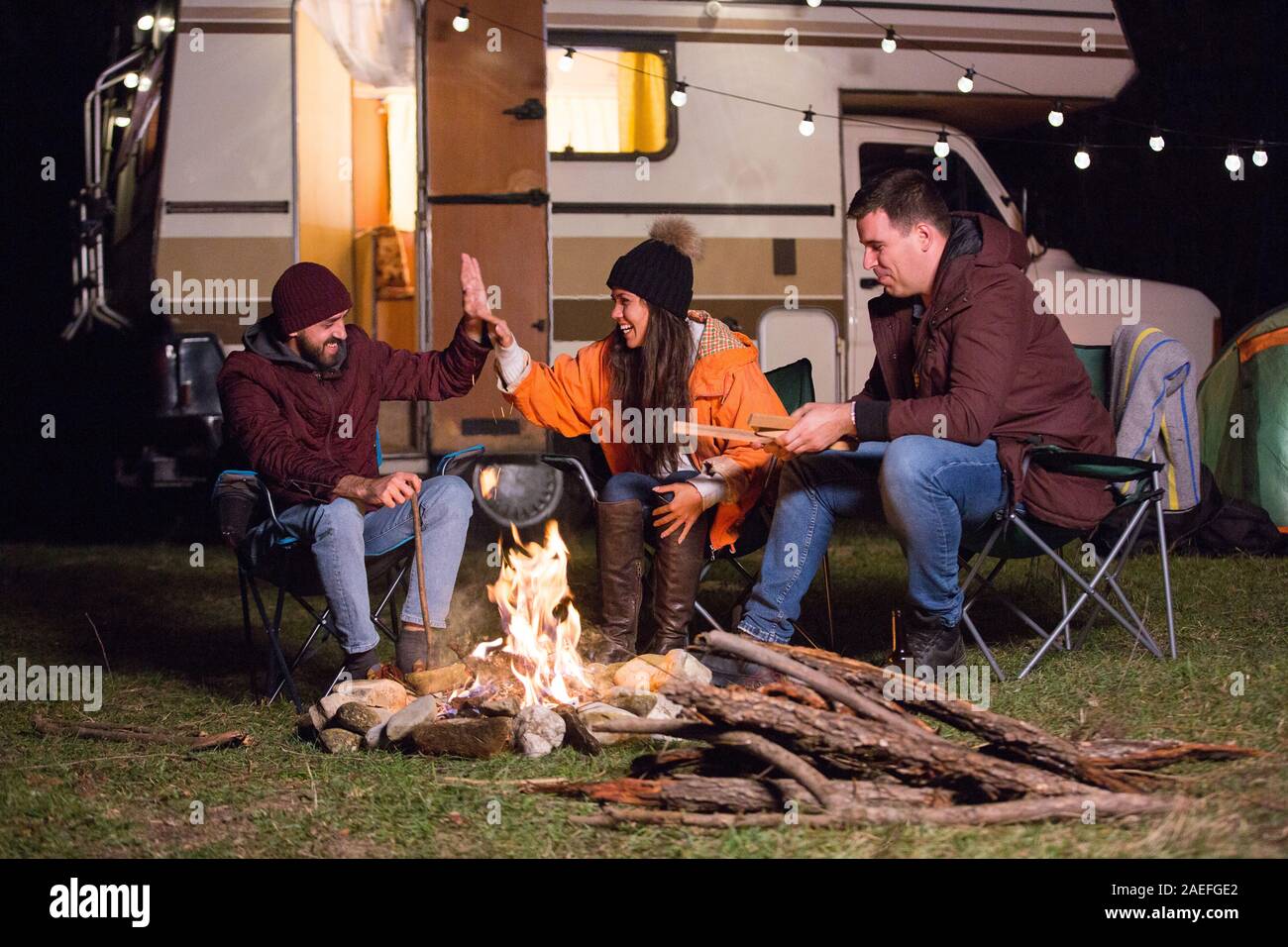 Tourists sitting around campfire warming hi-res stock photography and ...