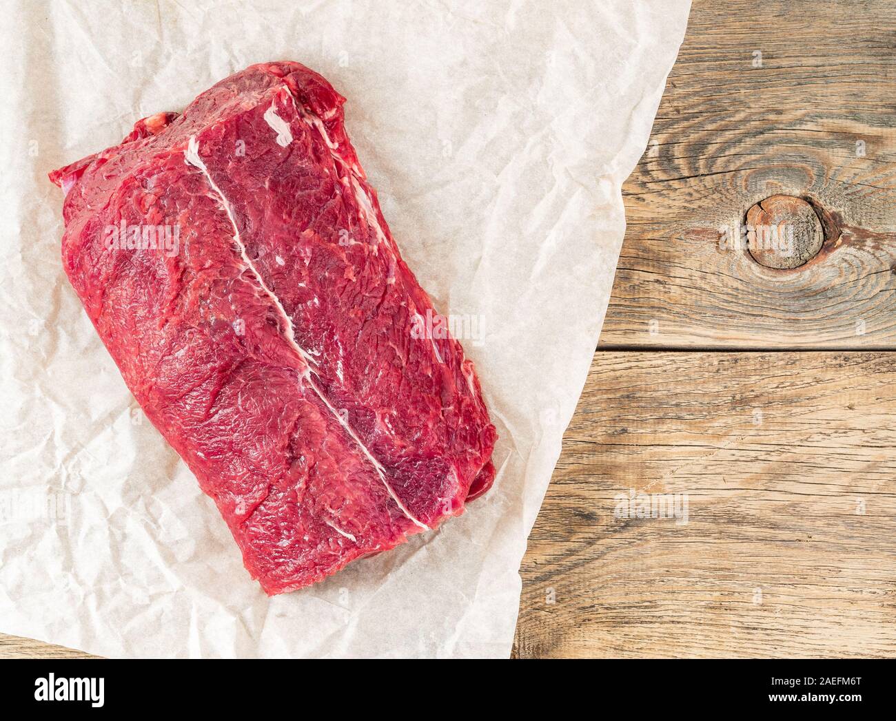 A large piece of raw meat. Beef tenderloin on white parchment paper on ...