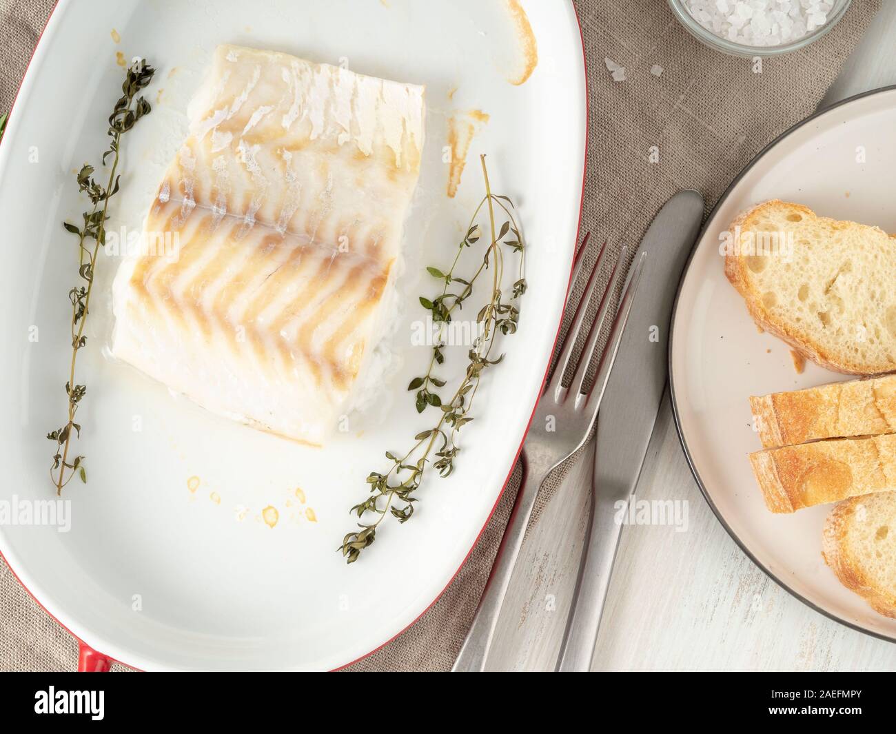 cod fish fillet, freshly cooked in oven with thyme in a porcelain dish ...