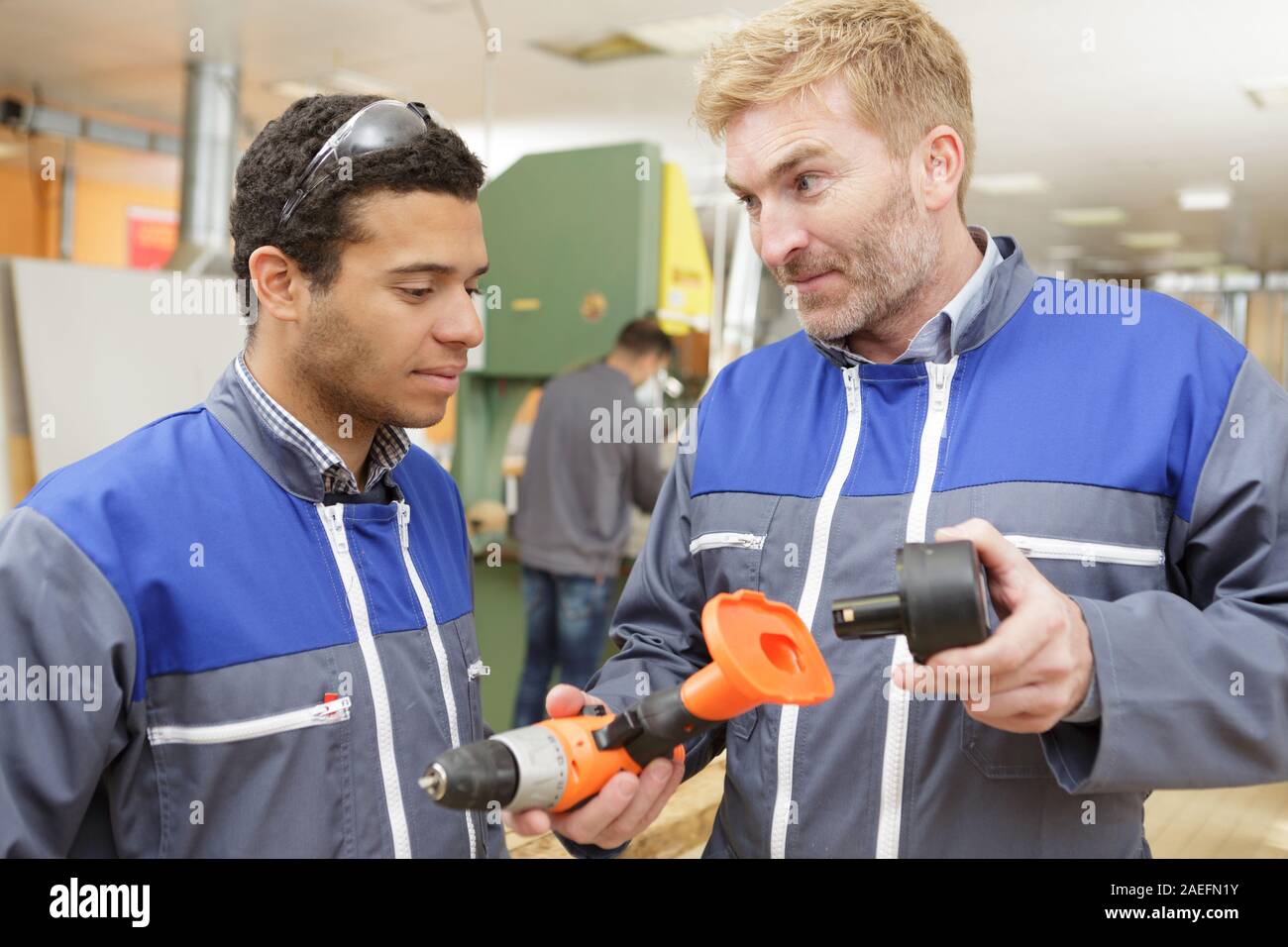 foreman showing apprentice how to fit battery in cordless drill Stock ...