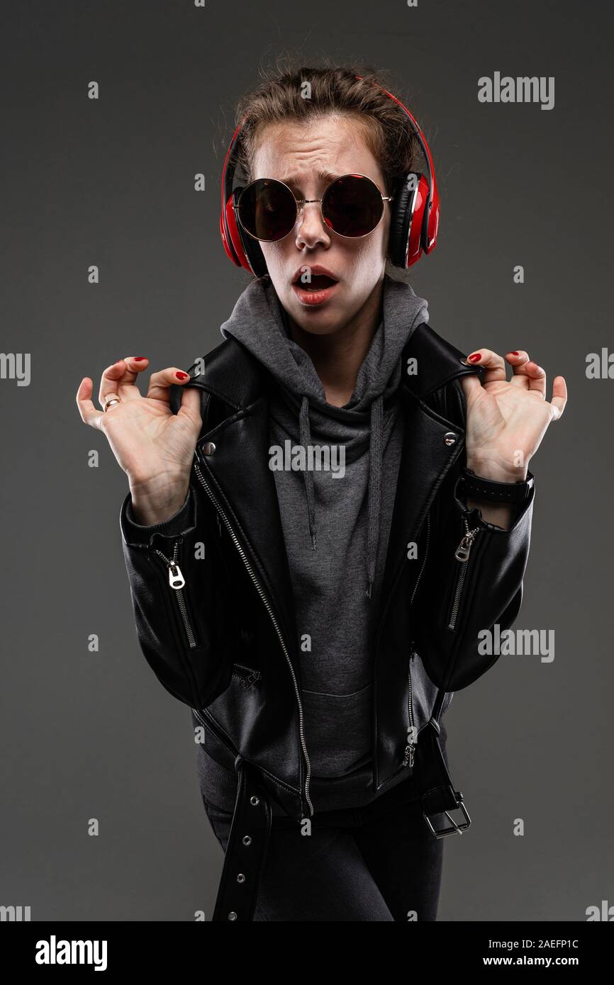Caucasian girl with rough facial features in a black jacket listen to ...