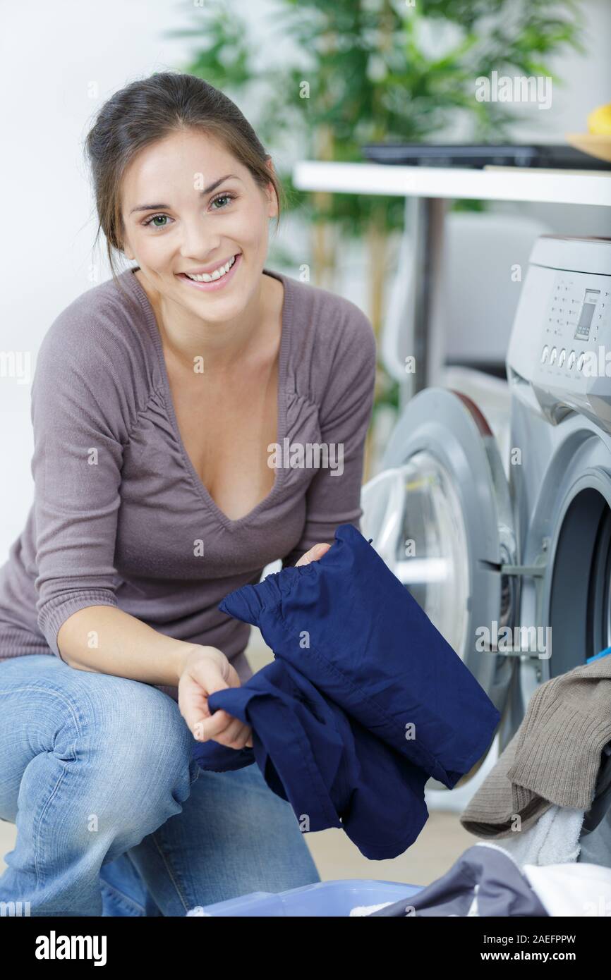 young woman loading clothes from basket in washing machine Stock Photo ...