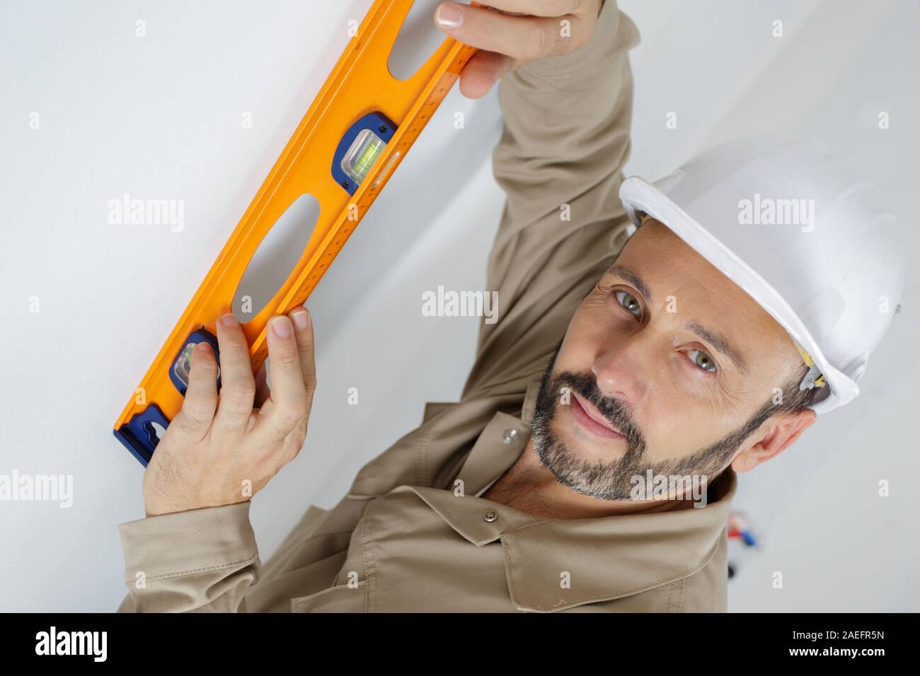 man posing with a builders level Stock Photo - Alamy