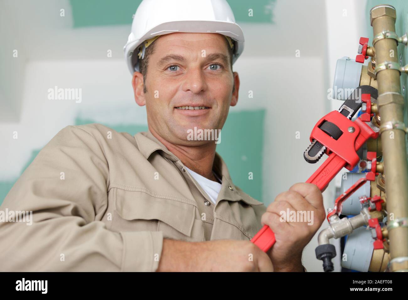 man fixing pipes while looking at camera Stock Photo - Alamy
