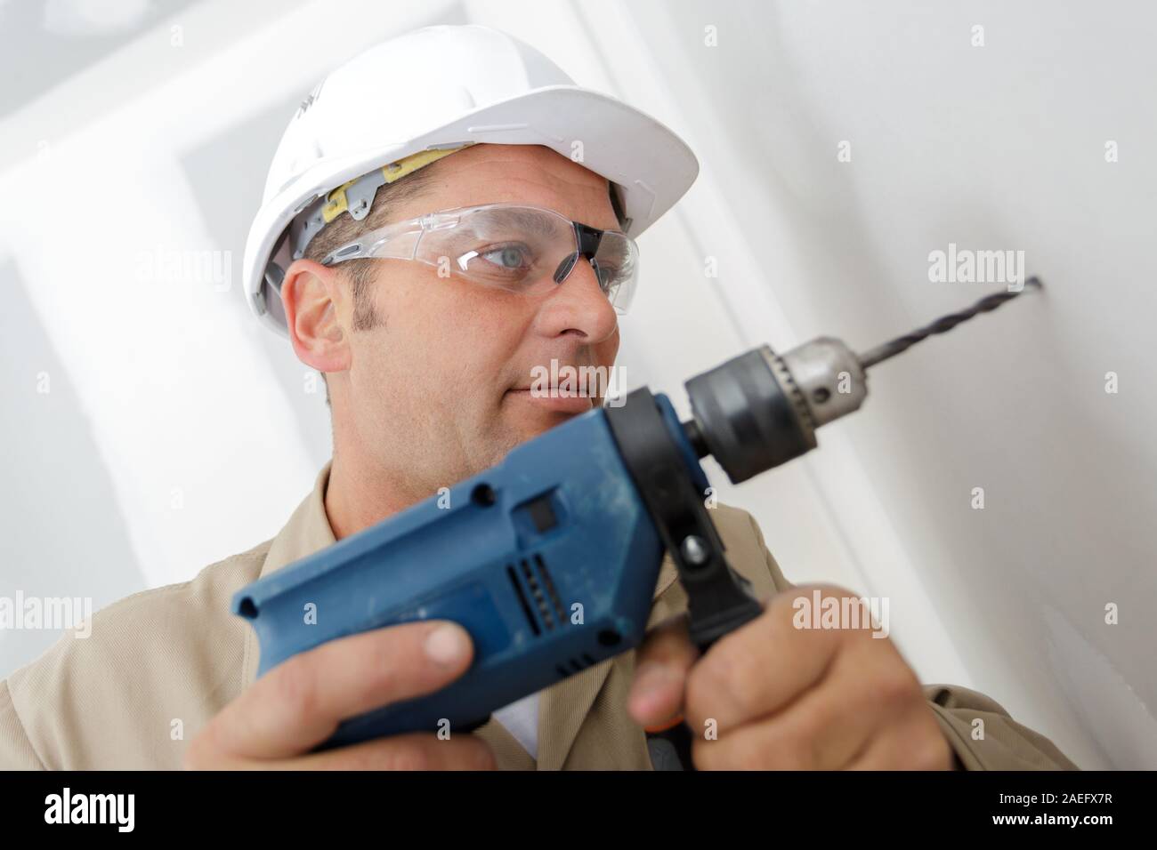 man drilling the wall with drill perforator Stock Photo - Alamy
