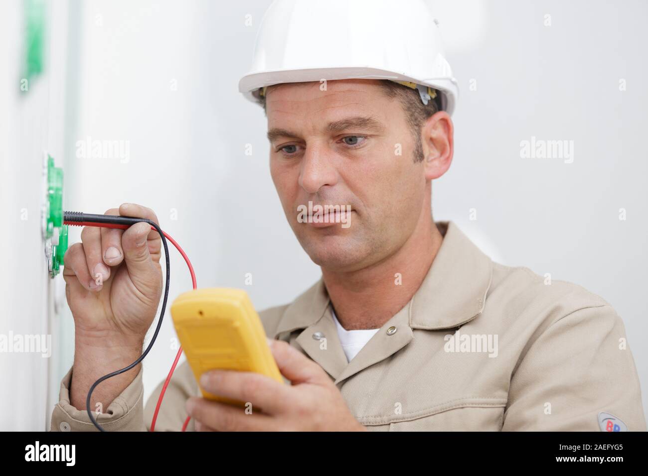 happy electrician checking voltage in electrical wall socket Stock ...