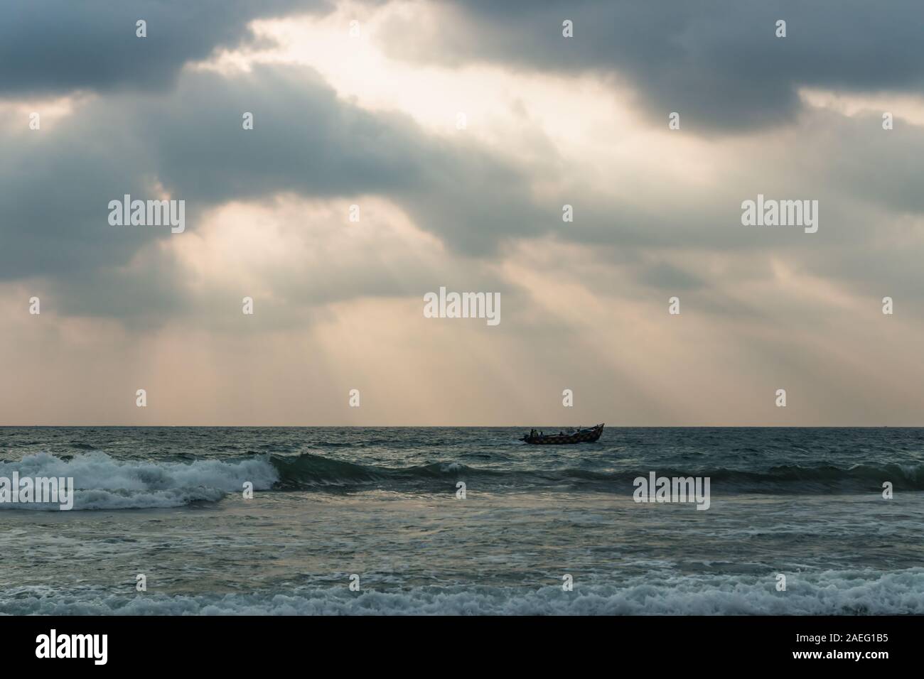 Fishing boat in the splash waves of the ocean with sun rays during ...