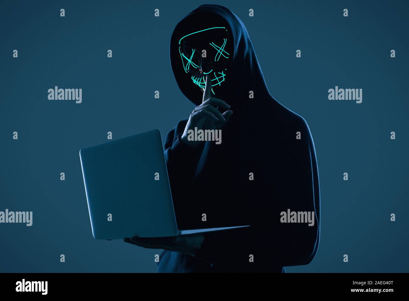 Portrait of an anonymous man in a black hoodie and neon mask hacking ...