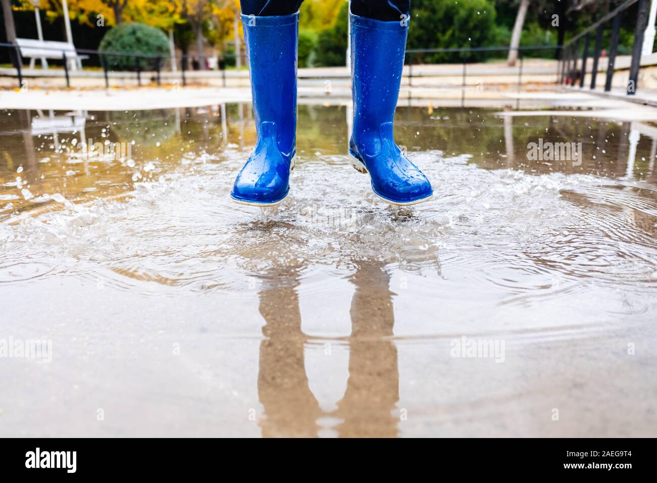 Boy with blue water boots jumps in a puddle Stock Photo - Alamy