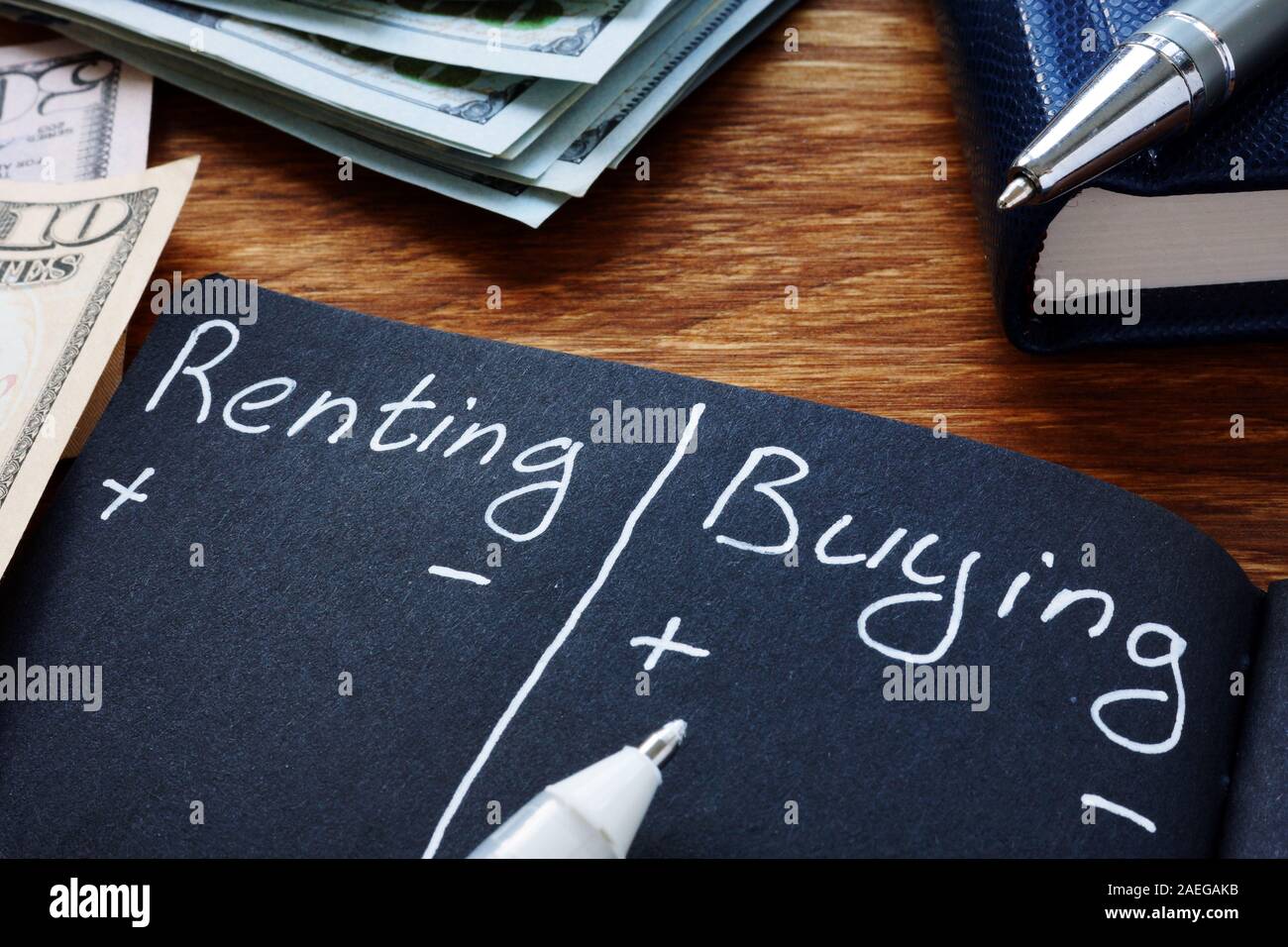 Renting vs buying comparison in the black notebook Stock Photo - Alamy
