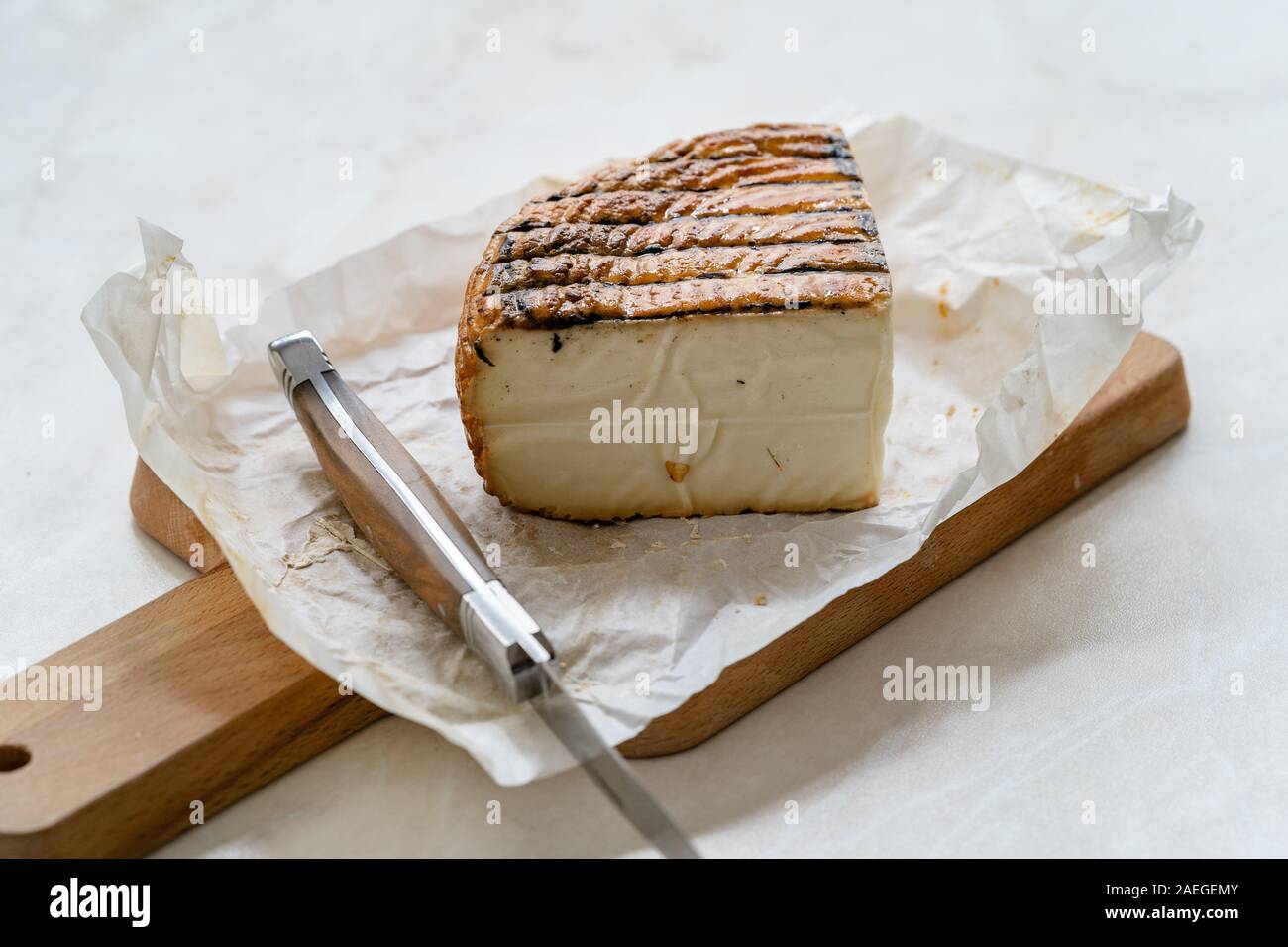 Triangle Cut Whole Smoked Cheese with Knife and Paper Sheer on Wooden ...