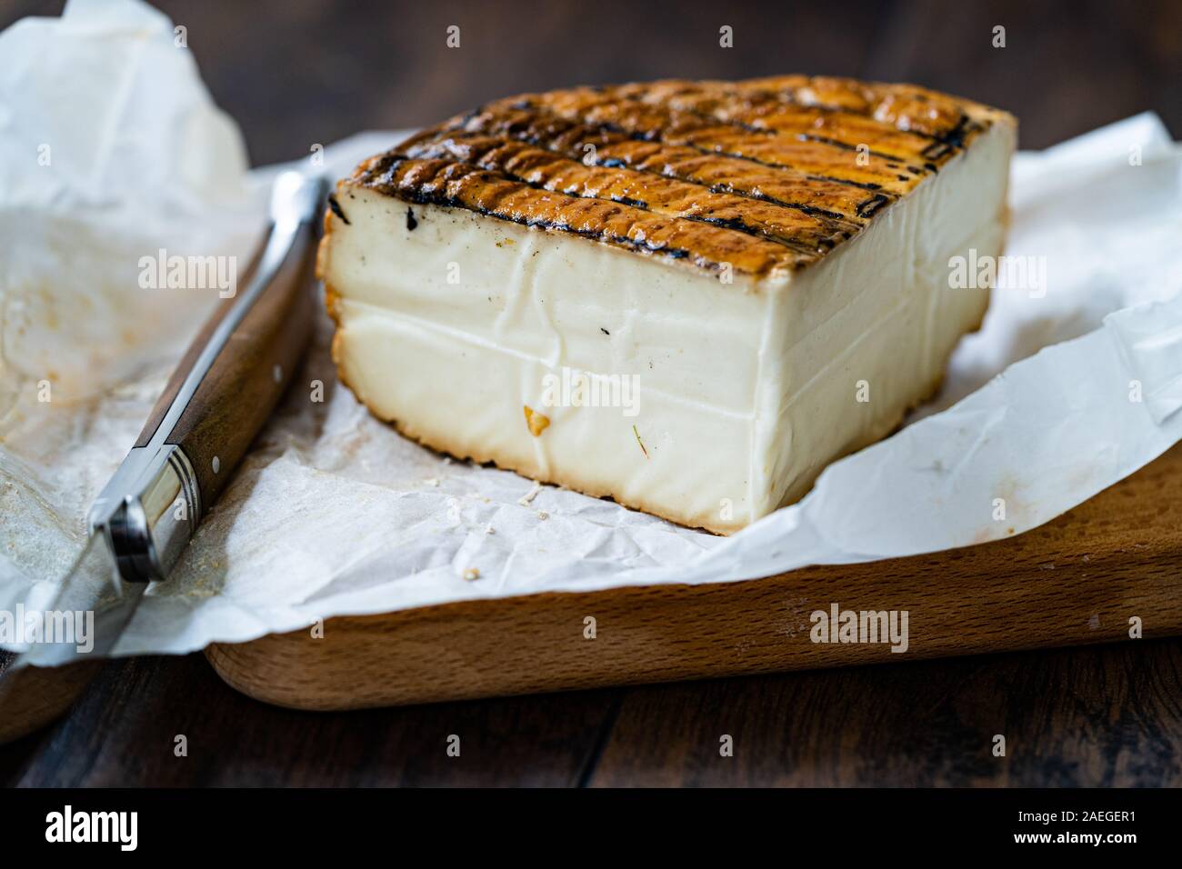 Triangle Cut Whole Smoked Cheese with Knife and Paper Sheer on Wooden ...