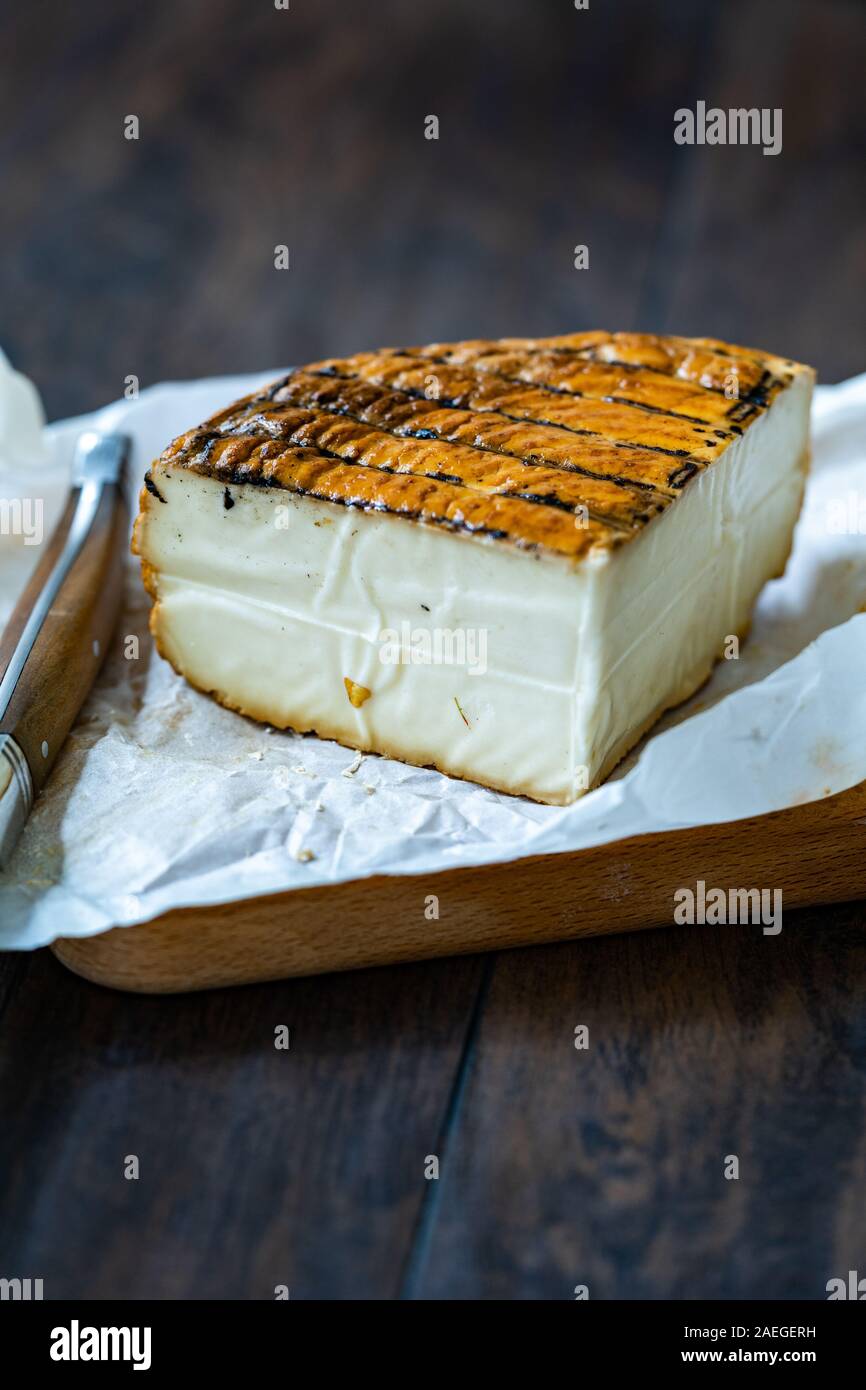 Triangle Cut Whole Smoked Cheese with Knife and Paper Sheer on Wooden ...
