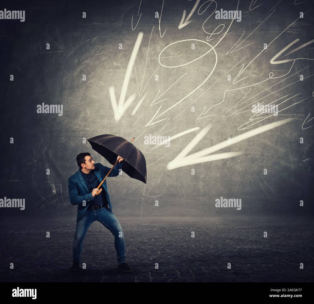 Determined businessman hiding behind umbrella as a shield to protect of ...
