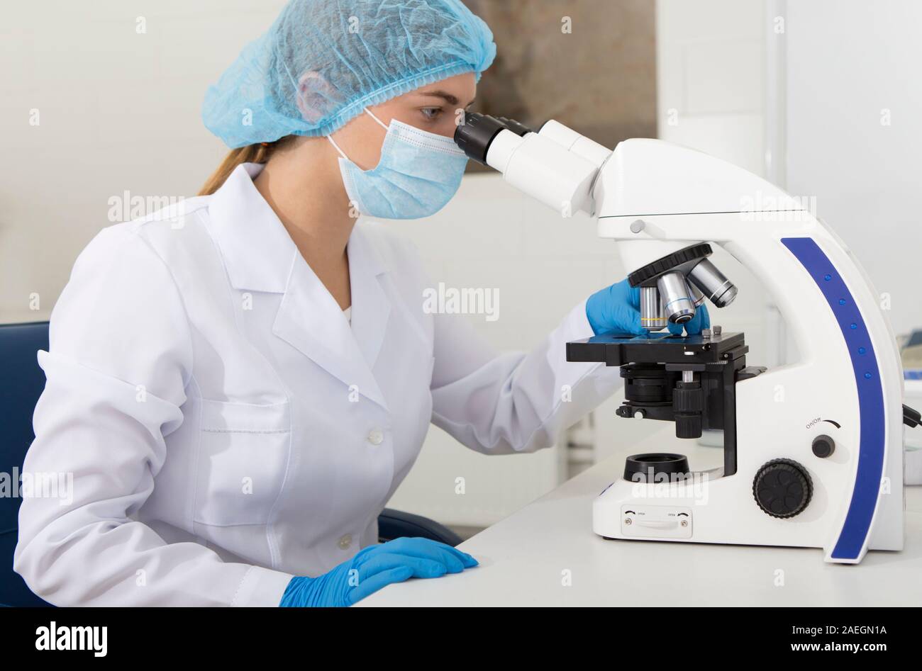 Young medical worker looking on samples through microscope Stock Photo ...