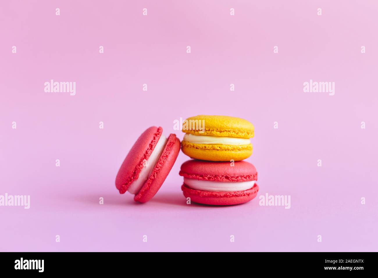 Three tasty french macarons on pink background. Close-up. Place for ...
