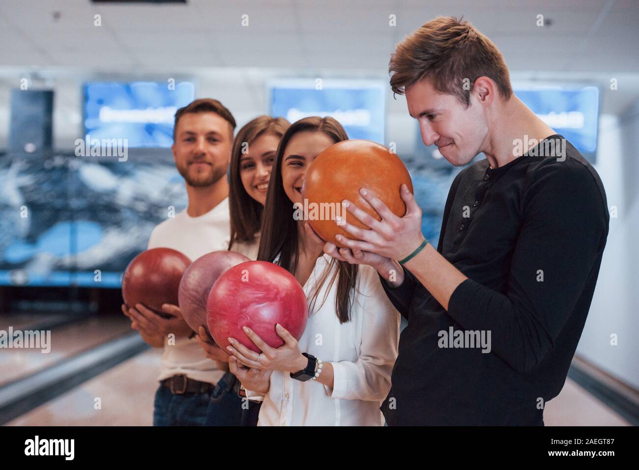 Making funny face. Young cheerful friends have fun in bowling club at ...