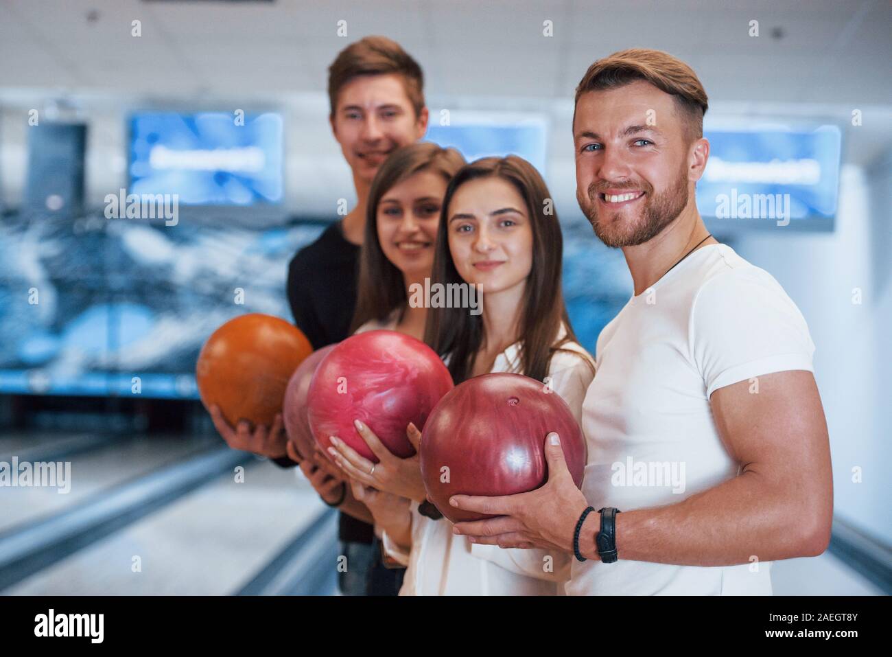 Sincere smiles. Young cheerful friends have fun in bowling club at ...