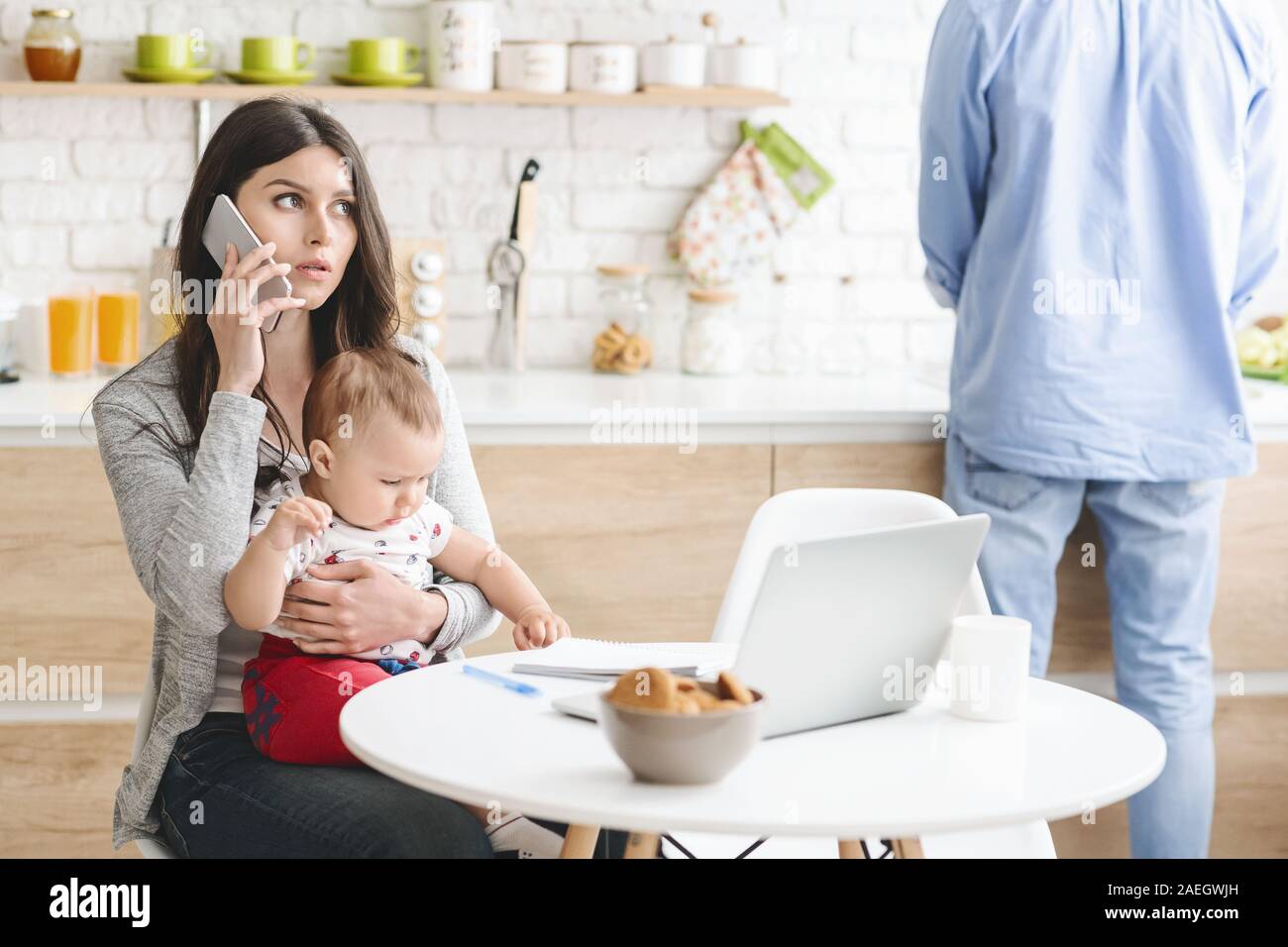 Serious business mom talking on phone, working from home with baby ...